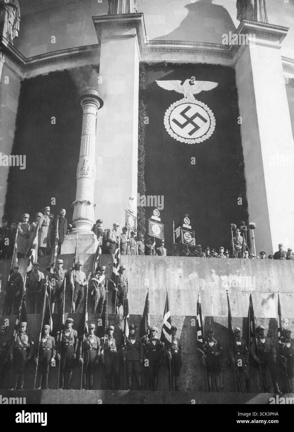 Reich Chancellor Adolf Hitler addresses a rally. The coat of arms of ...