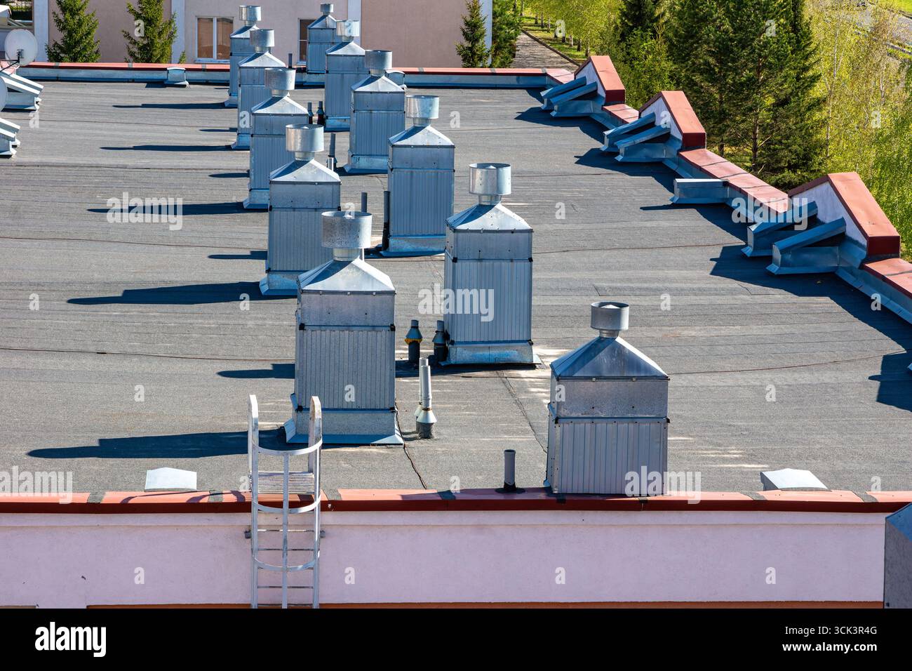 A neat row of silver ventilation pipes on a flat roof, showing how buildings are designed to ...