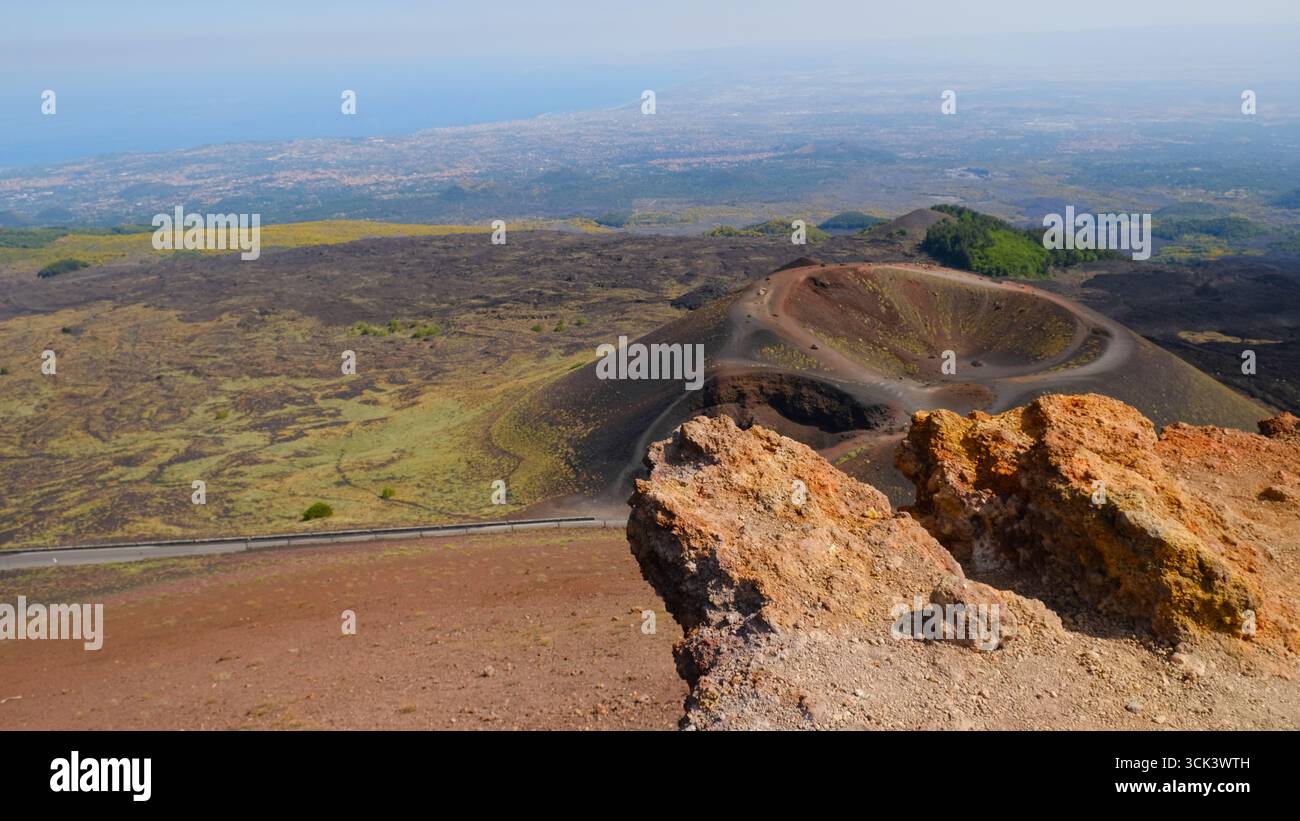 Rugged volcanic landscape with large, rust-colored rock, and cinder ...
