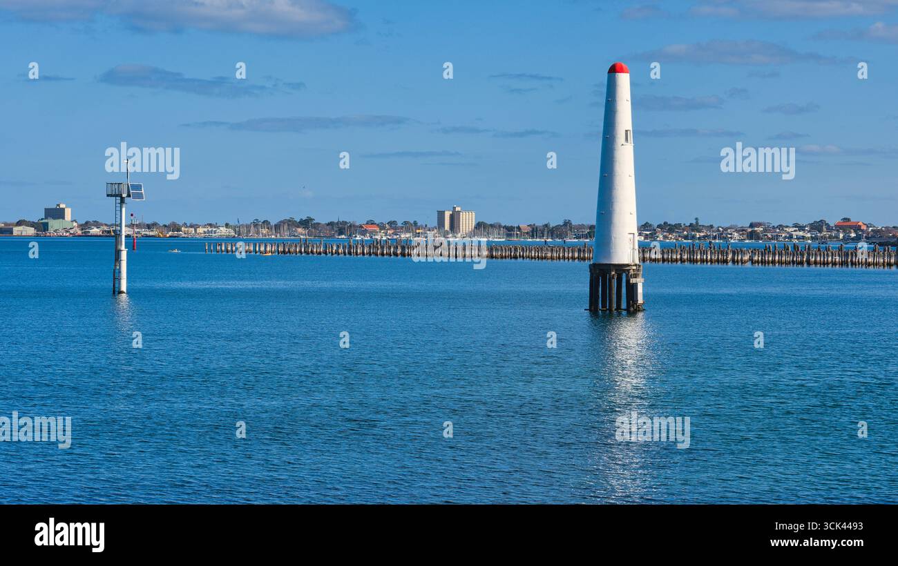 Tall white navigation beacon in Port Phillip Bay with Port Melbourne ...