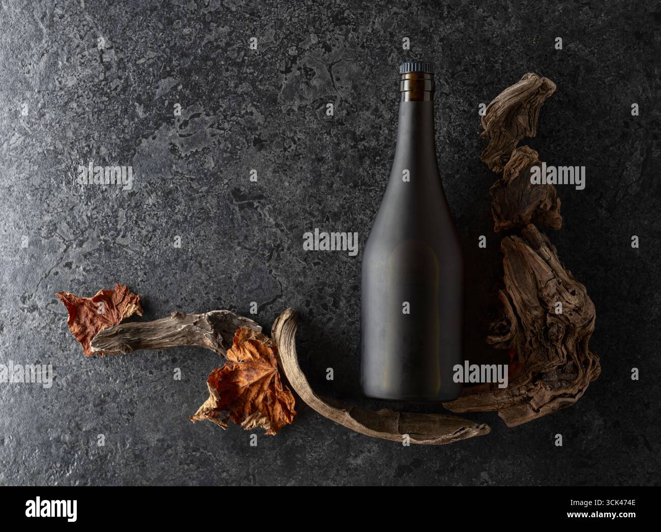 Vintage bottle of brandy and old snags on a black stone background. Top ...