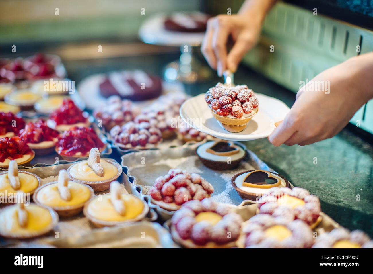 Woman takes tartlets from the pastry buffet Stock Photo - Alamy