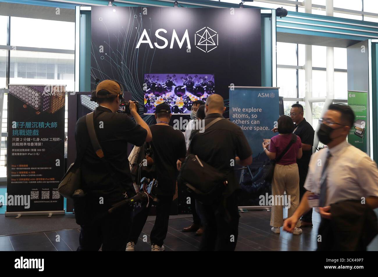 Visitors walk by ASM booth during the SEMICON Taiwan exhibition at ...