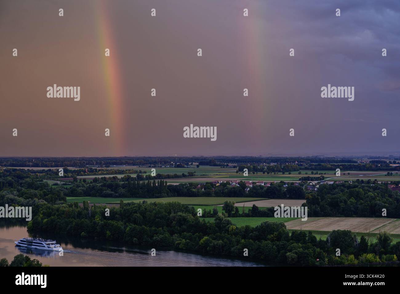 A magnificent rainbow stretches across the green landscape while a ship ...