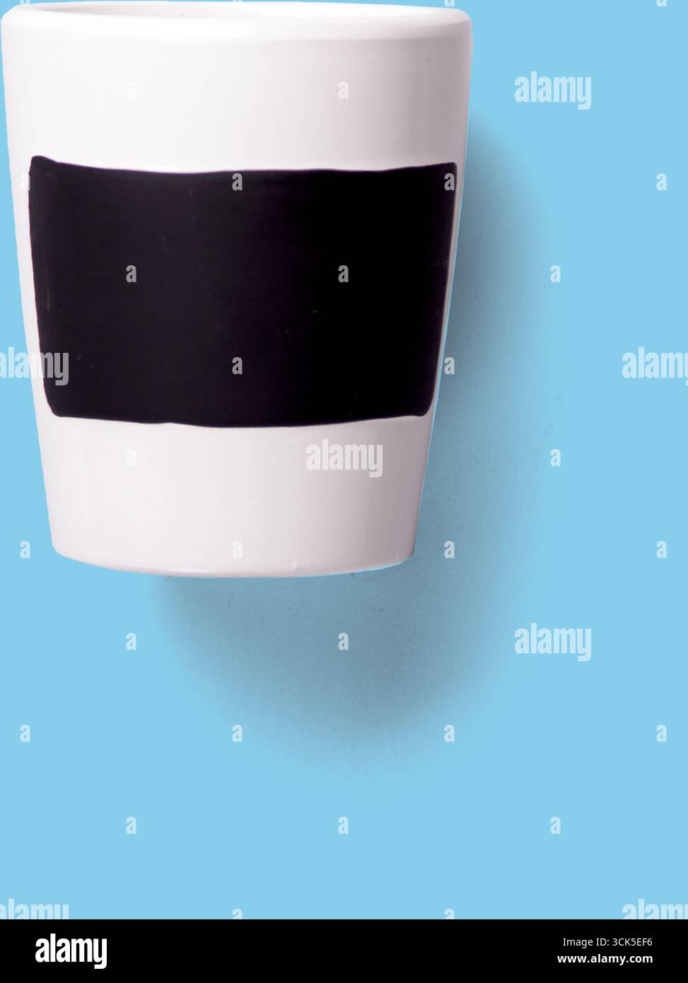 A minimalist white cup with a black band, casting a shadow Stock Photo ...