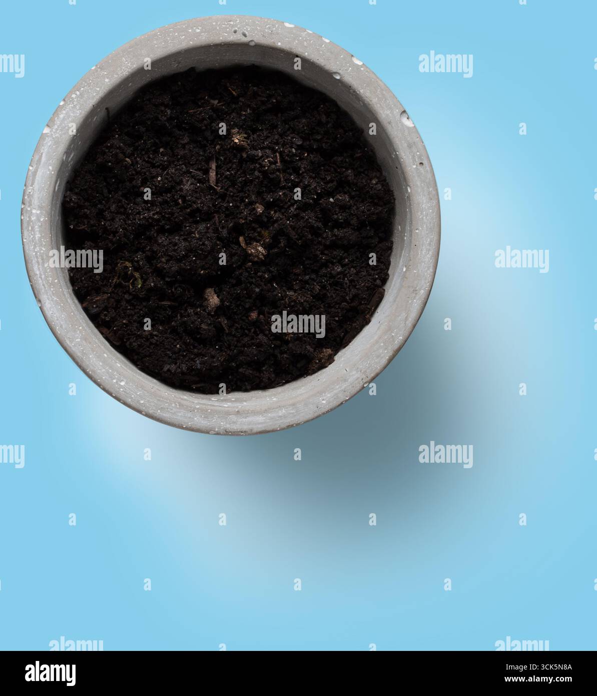 A small pot filled with dark soil, ready for planting seeds or ...