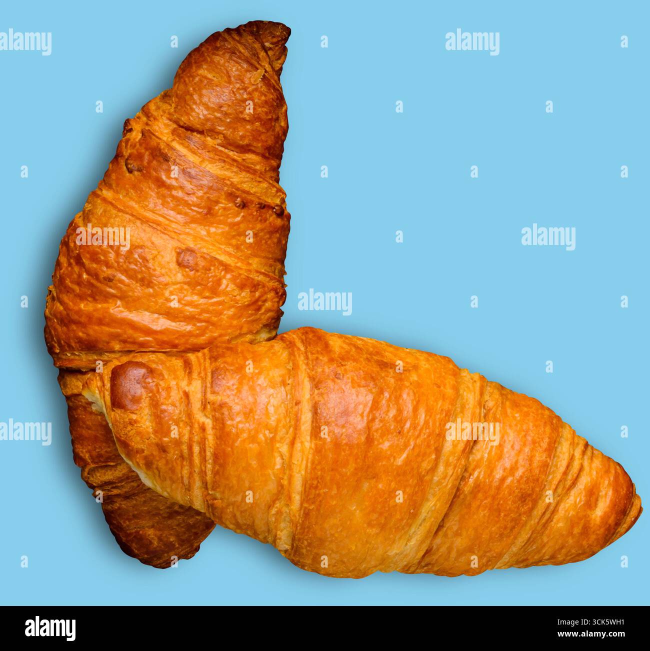 Two golden-brown croissants with a flaky texture, showcasing a ...