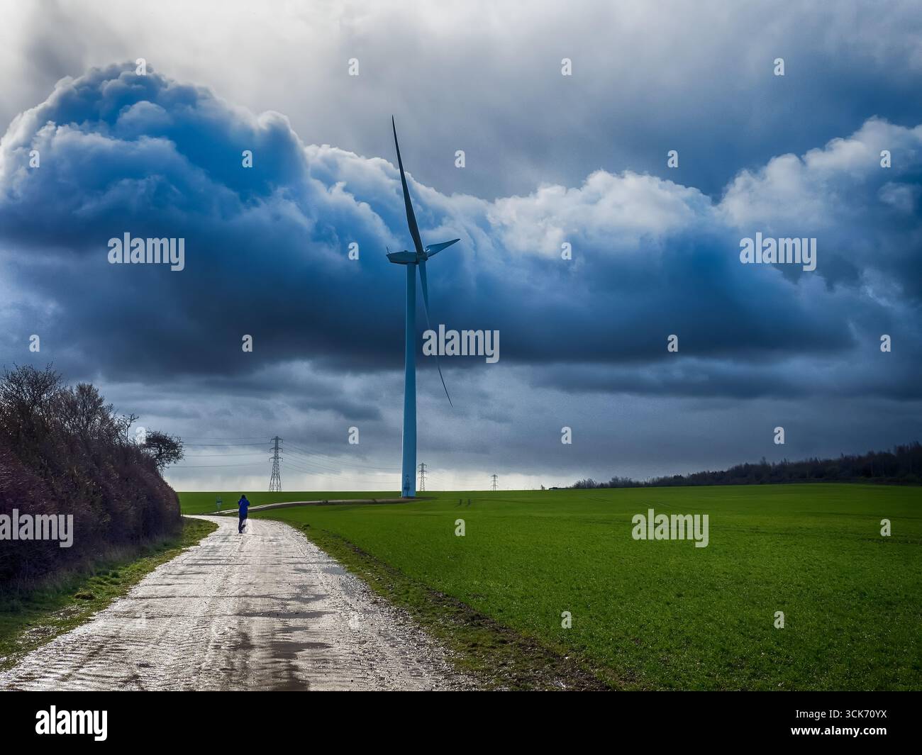 Wind turbine and walker beneath dramatic storm clouds Stock Photo - Alamy