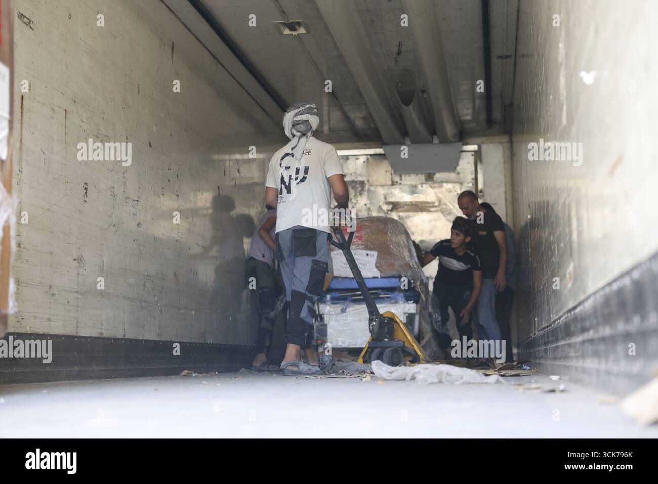 Relief workers unload boxes of medical aid provided by Qatar at ...