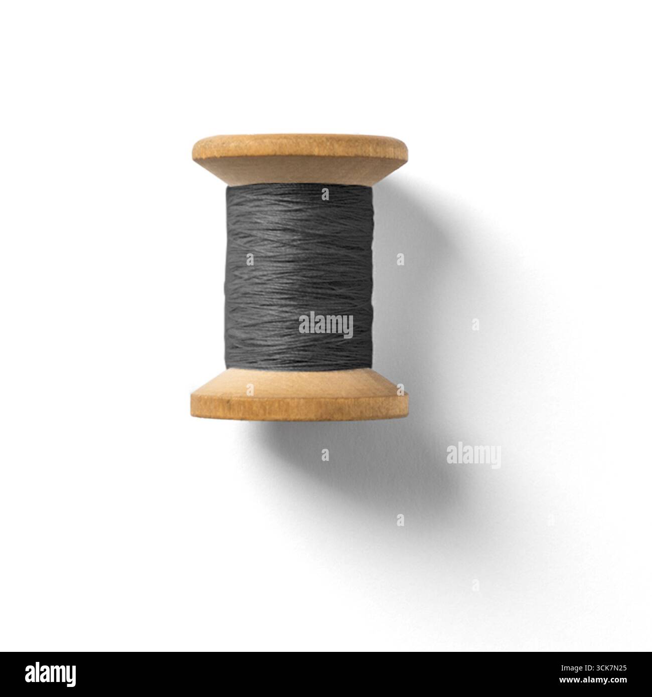 A wooden spool holding dark thread, commonly used in sewing and ...