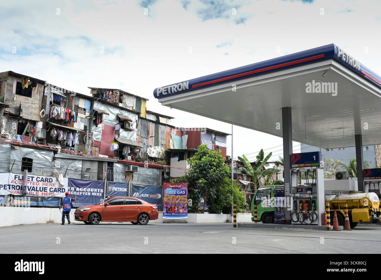 PHILIPPINES, Manila, Quezon City, Petron petrol station and slum huts ...