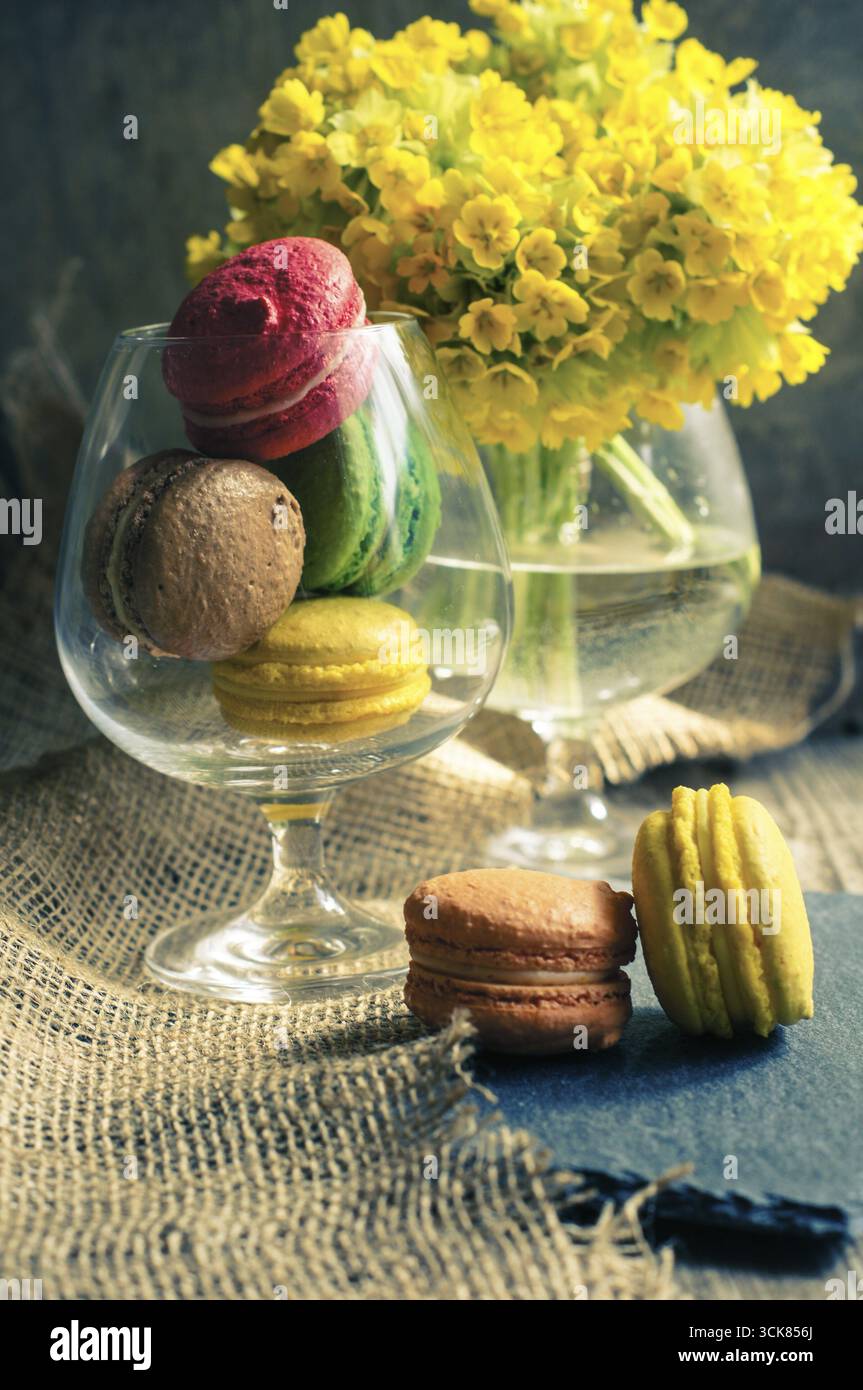 Colorful macaroons and first spring flowers on old wooden background ...