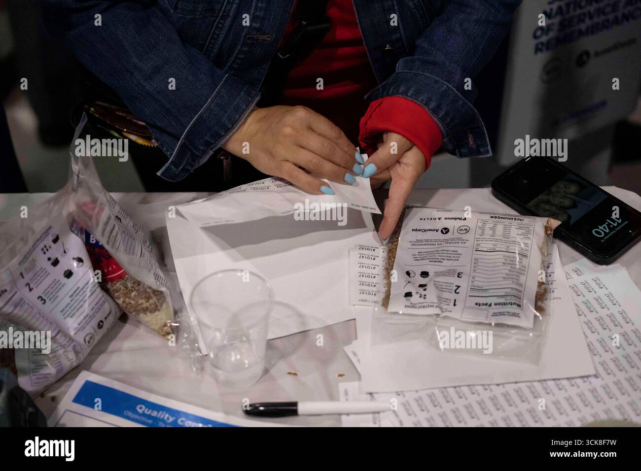 A volunteer puts labels on the bag during the "NYC Meal Pack For 9/11 ...
