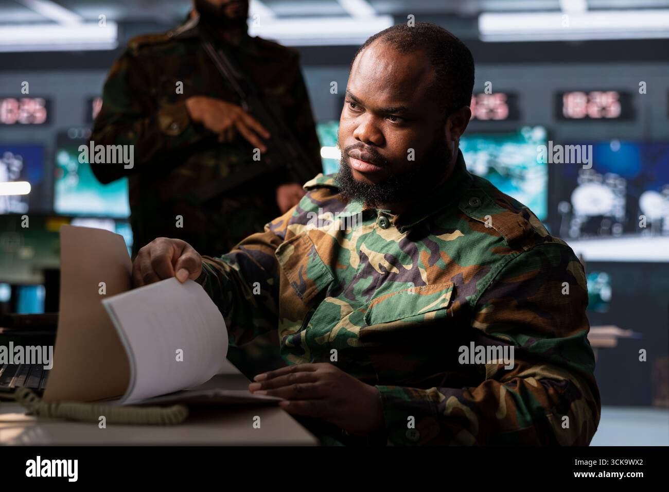 Military agent in command center browsing through intel folder files to learn about enemy battle ...