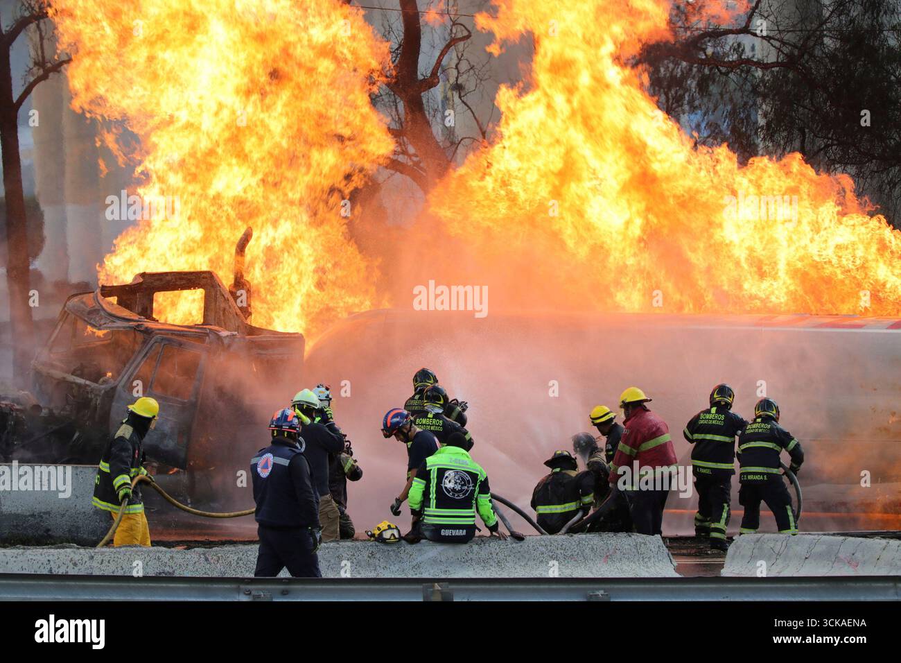 Firefighters spray hoses at a gas tanker that exploded under a highway ...