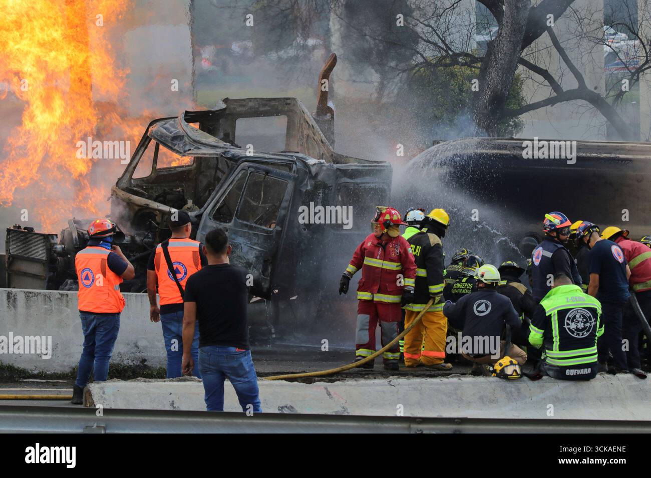 Firefighters spray a hose at a gas tanker that exploded under a highway ...
