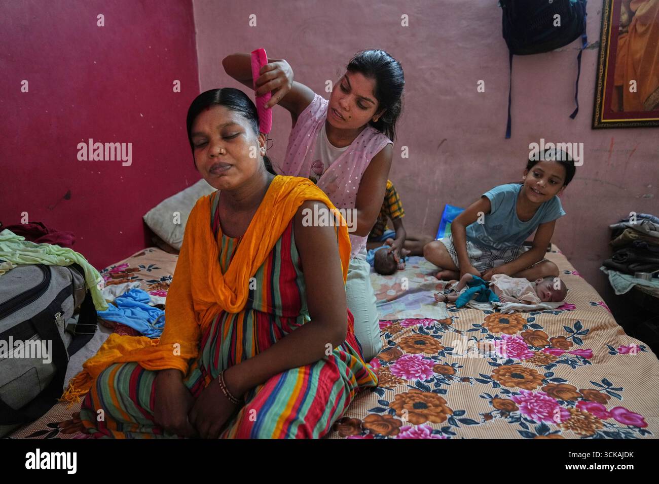 Antima Kumari, center, trained in Care Companion Program (CCP), combs the hair of her sister ...