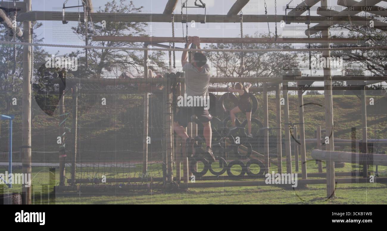 Climbing athletic male swinging on hanging rings in grassy park ...