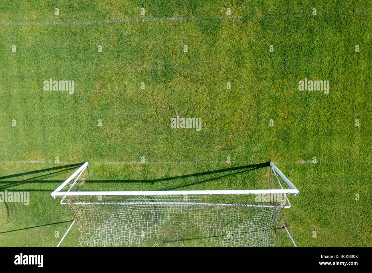An empty football goal casting a long shadow on the pitch Stock Photo ...