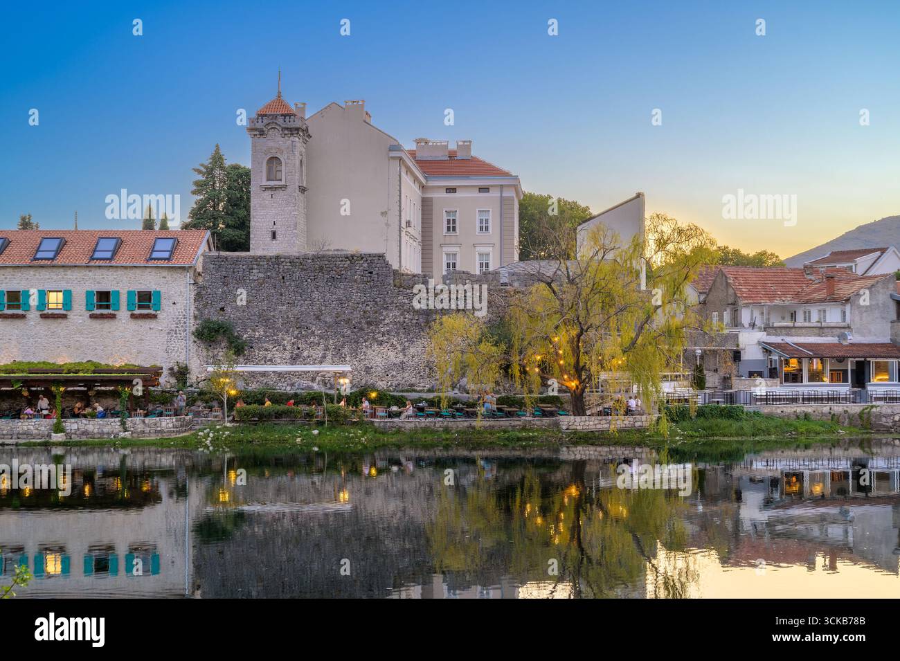 Sunlight fades behind medieval structures as the river reflects the ...