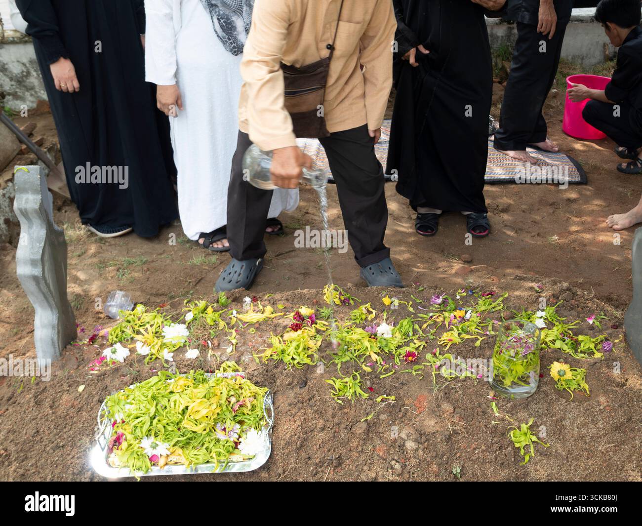 Pouring water on newly buried body during a traditional Malay funeral ...