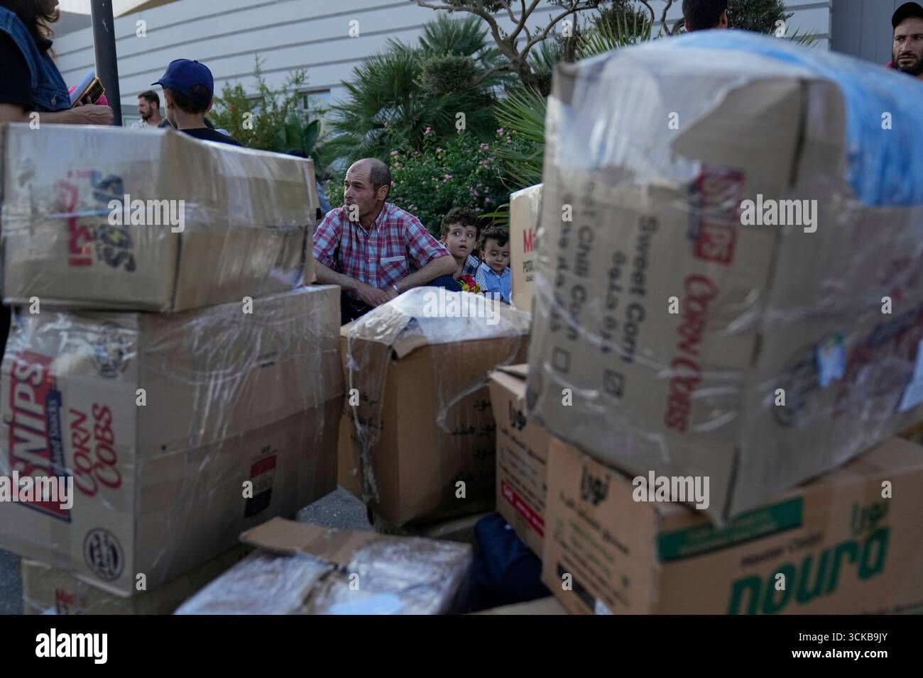 Members of a Syrian refugee family sit next their belongings at a ...