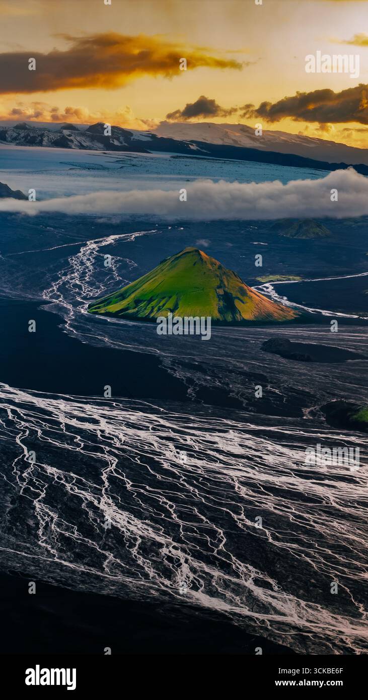 Aerial image of a green cone shaped hill on dark volcanic terrain, with ...