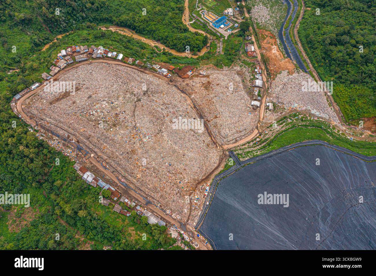 Aerial view of a large landfill surrounded by greenery and small ...