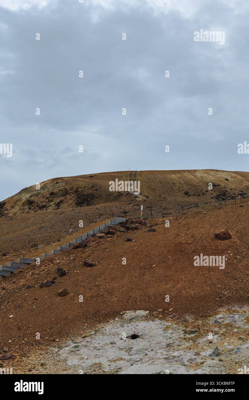 A rocky, barren hill with a winding path marked by wooden steps and a ...