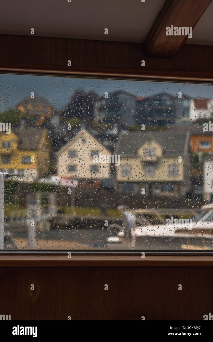 A view through a rain speckled window shows a Norwegian harbor town ...