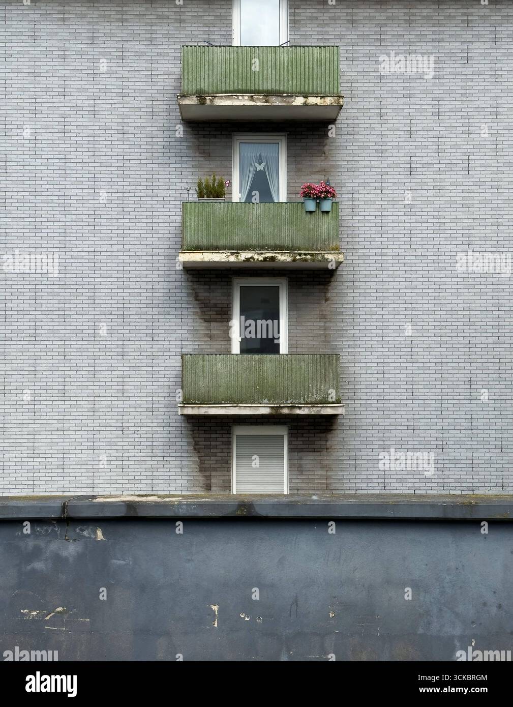 Eine Hausfassade eines Mehrfamilienhaus mit Bitumenklinker und Balkonen ...