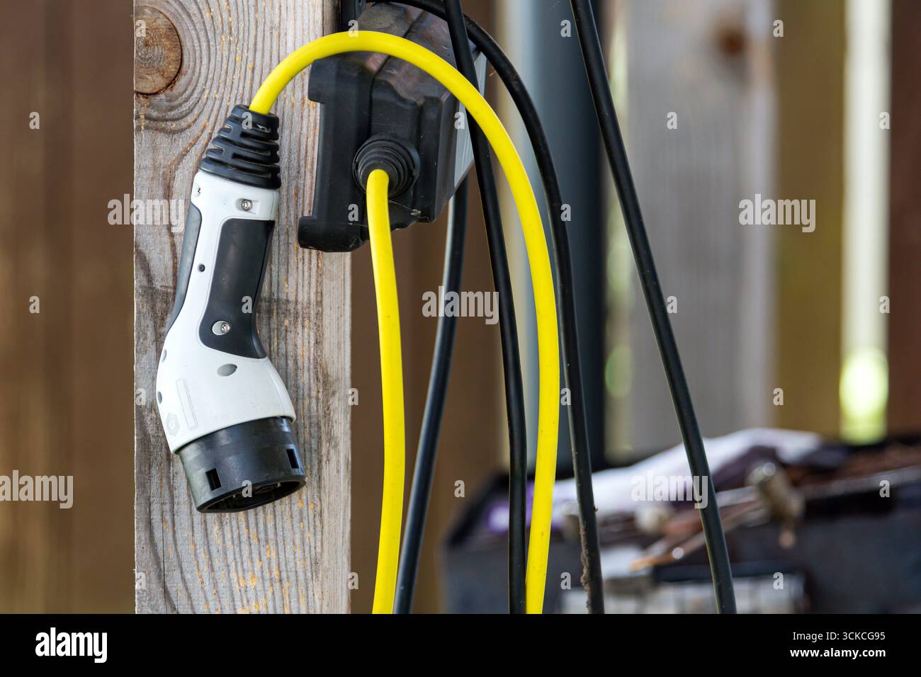 Electric charging connector hangs from wooden post next to tangled ...