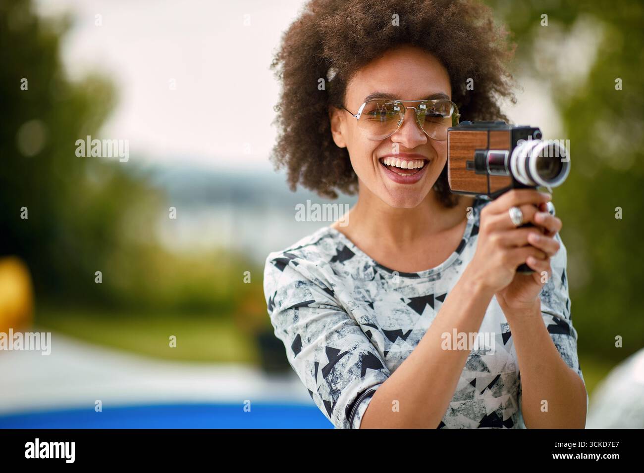 Young joyful woman feeling happy and holding video camera while ...