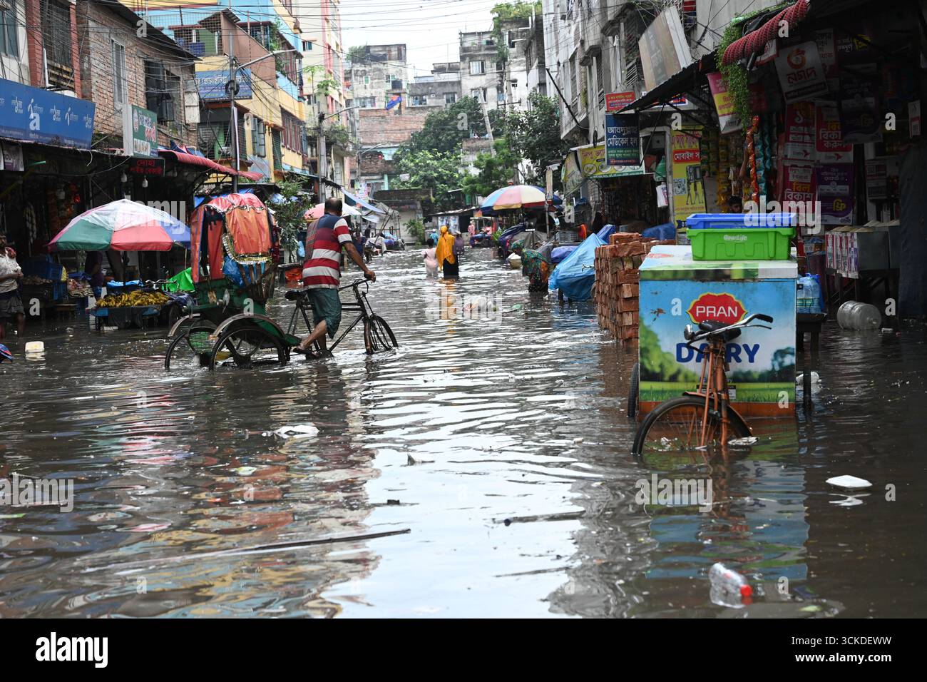 Vehicles and rickshaws drive with passengers through the waterlogged streets of Dhaka ...