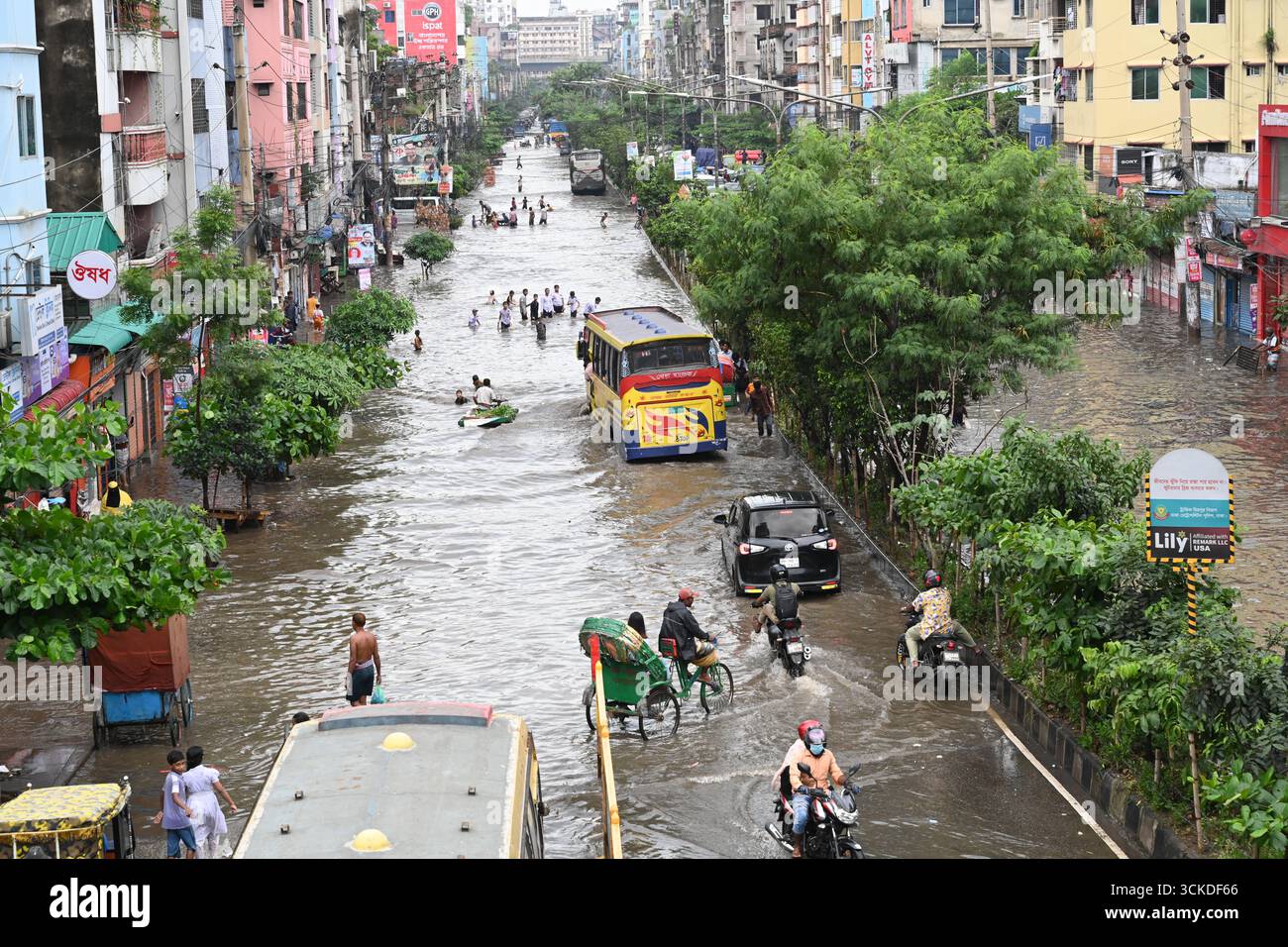 Vehicles and rickshaws drive with passengers through the waterlogged streets of Dhaka ...
