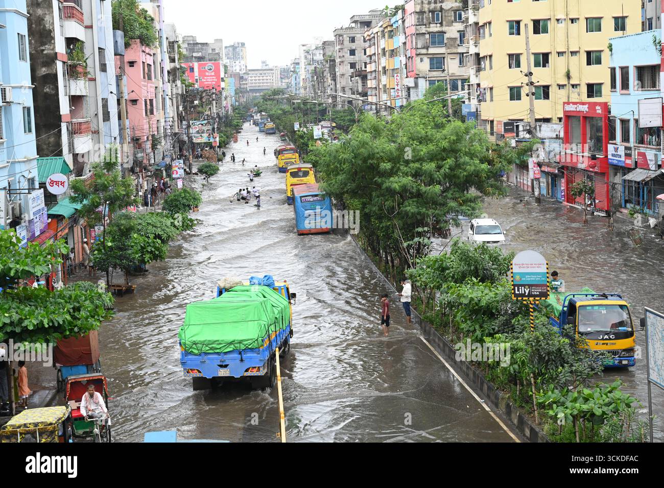 Vehicles and rickshaws drive with passengers through the waterlogged streets of Dhaka ...