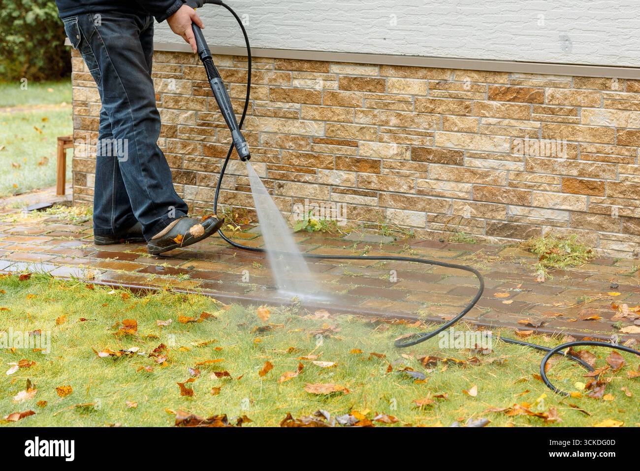 Man cleaning street with high pressure power washer, washing stone ...