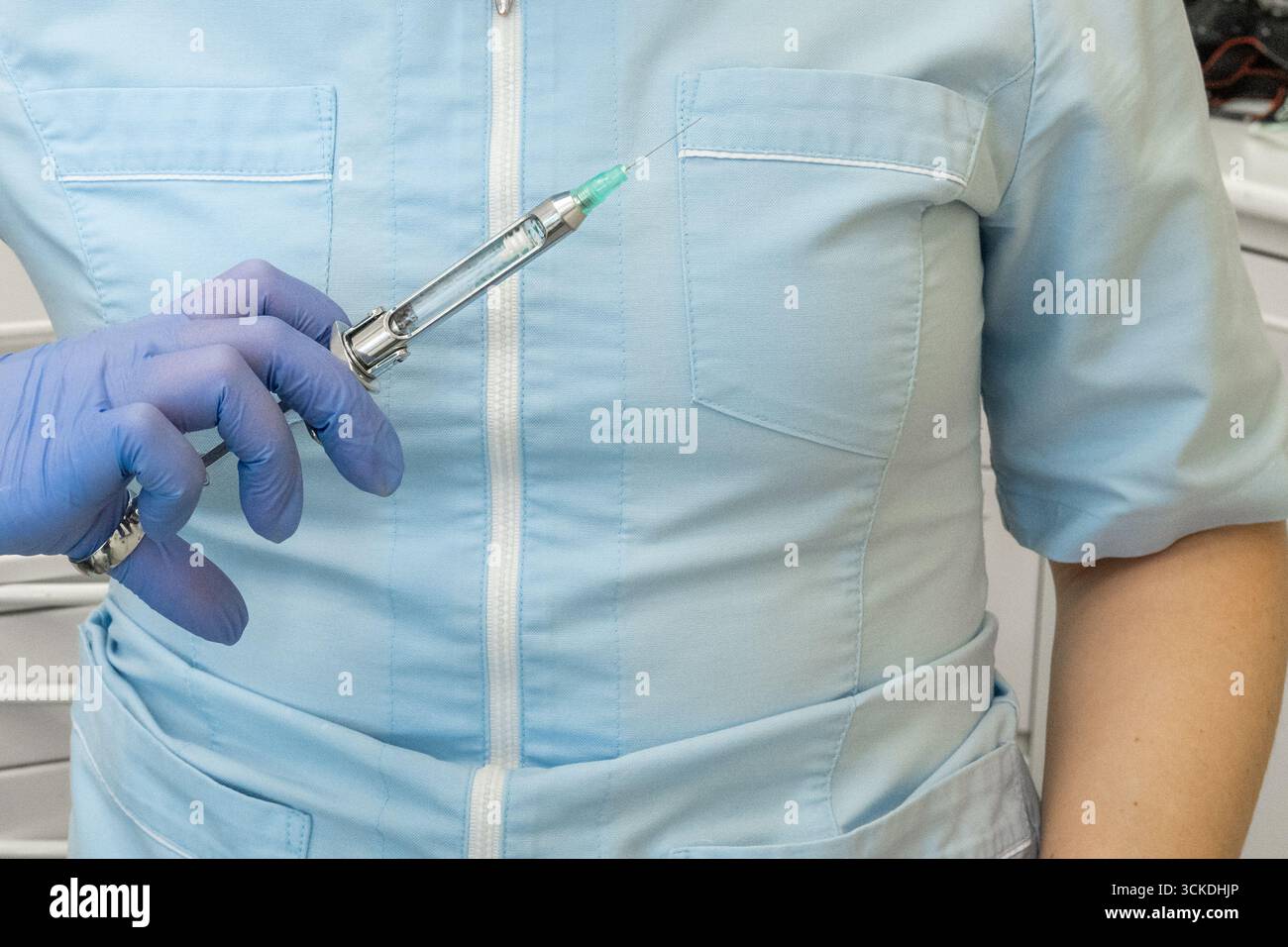 Doctor in medical gown and gloves holds syringe in her hand for ...