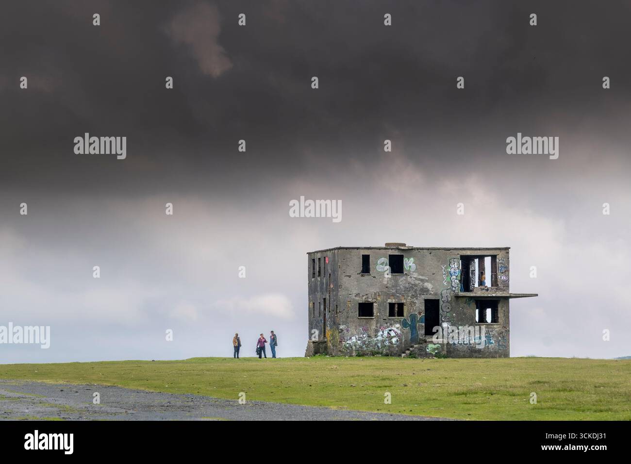 Three people standing near the remains of the disused control tower ...