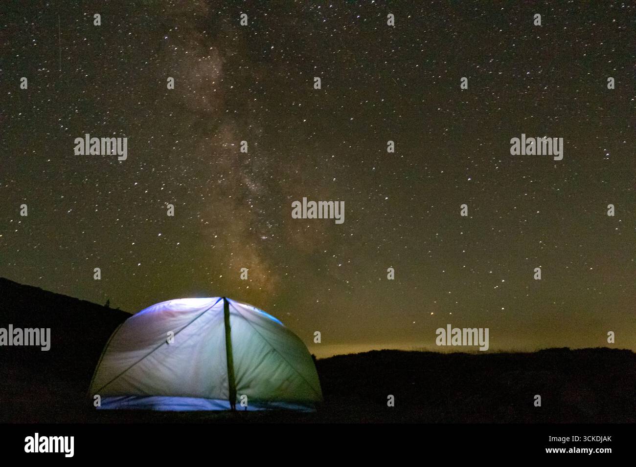 Tent at night under a clear starry sky, camping in the mountains ...
