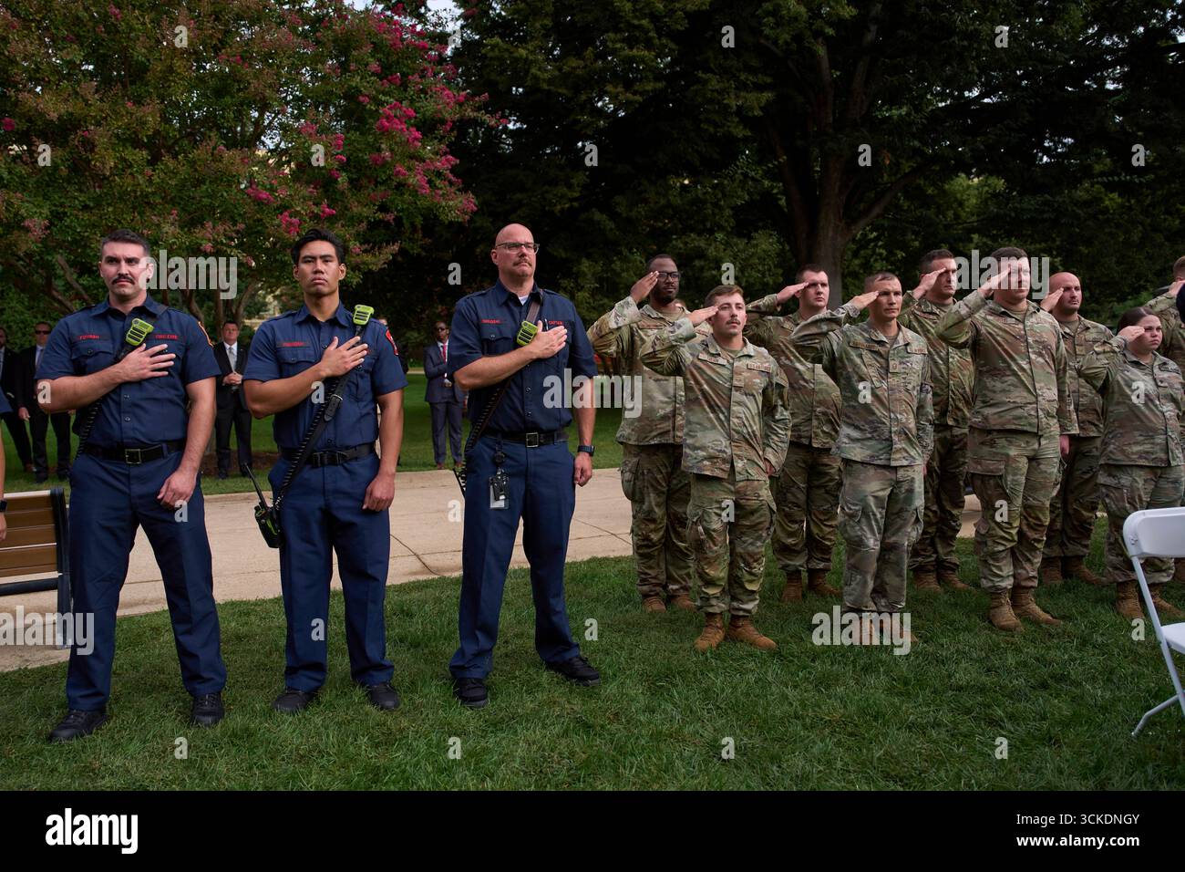 First responders and military personnel stands for the National Anthem during a ceremony to ...