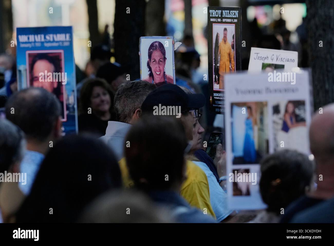People hold up pictures of family members during a ceremony to mark the ...