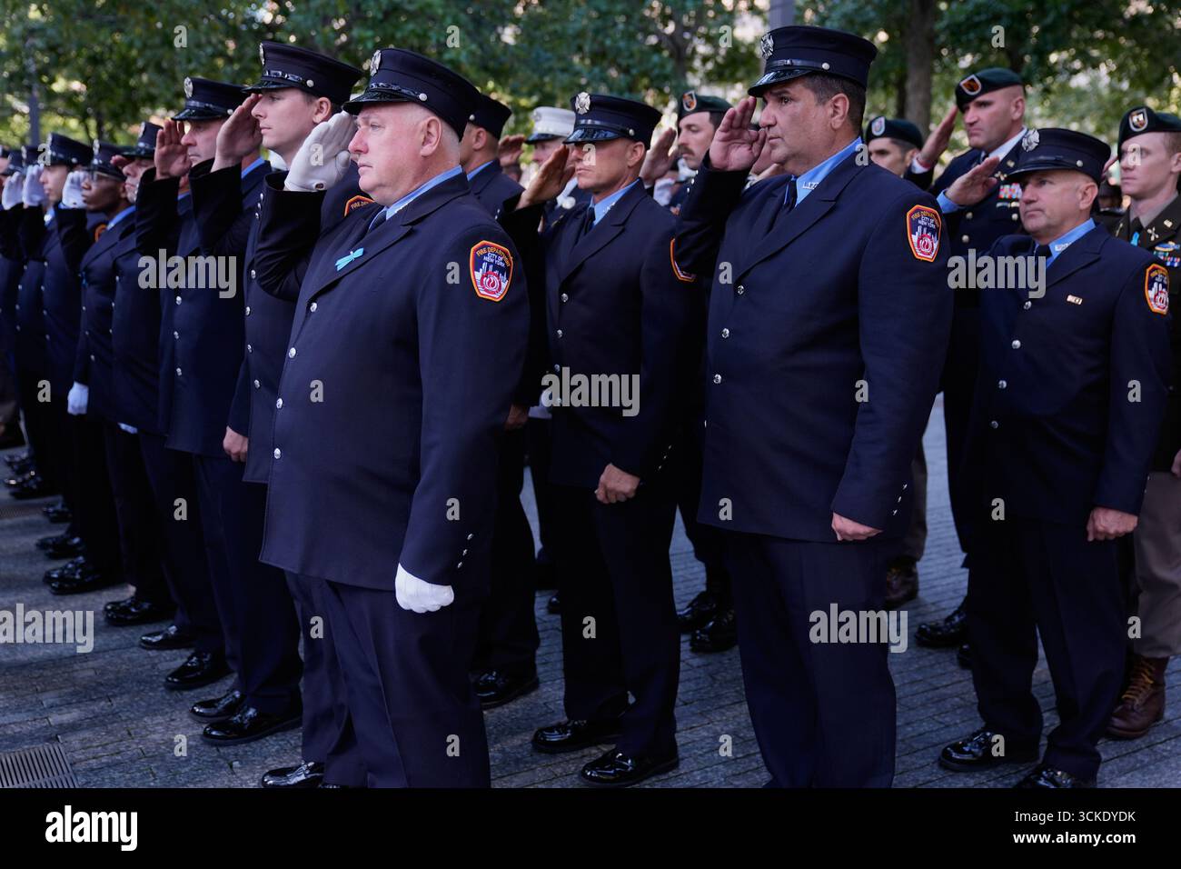Firefighters salute during a moment of silence during a ceremony to ...