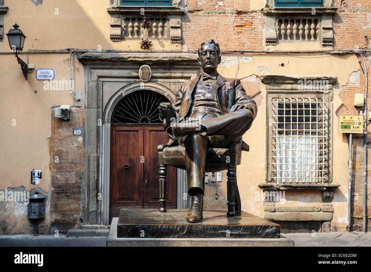 Bronze statue of the composer Puccini, depicted in a relaxed pose on a ...