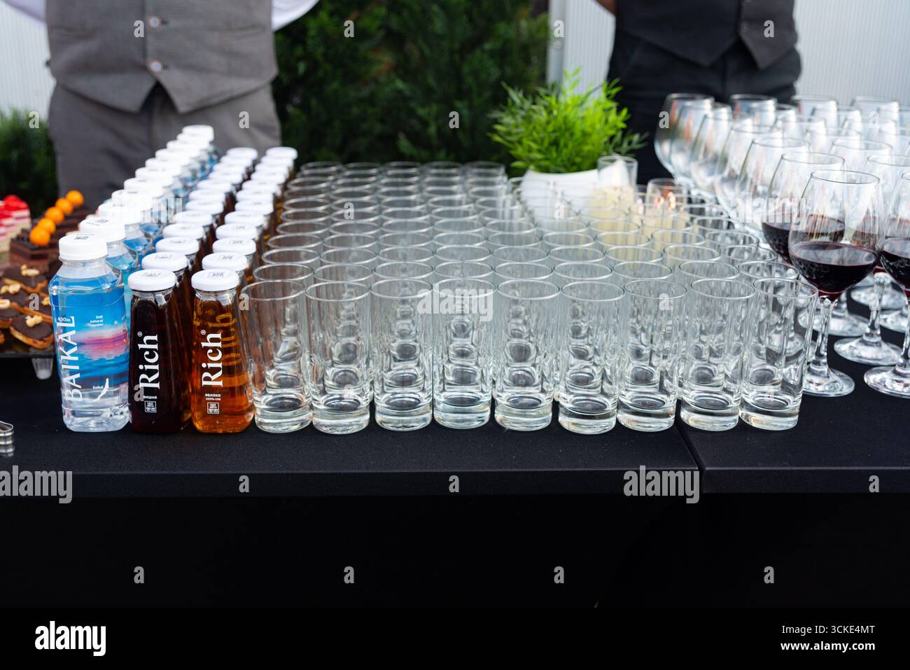 Variety of glassware and beverages on a black table at an outdoor event ...