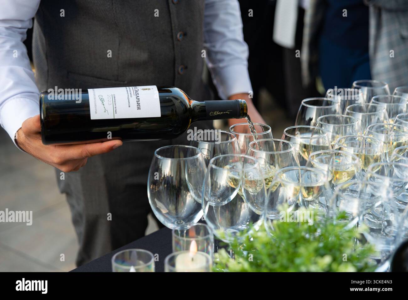 Wine pouring ceremony with glasses and greenery at outdoor event Stock ...