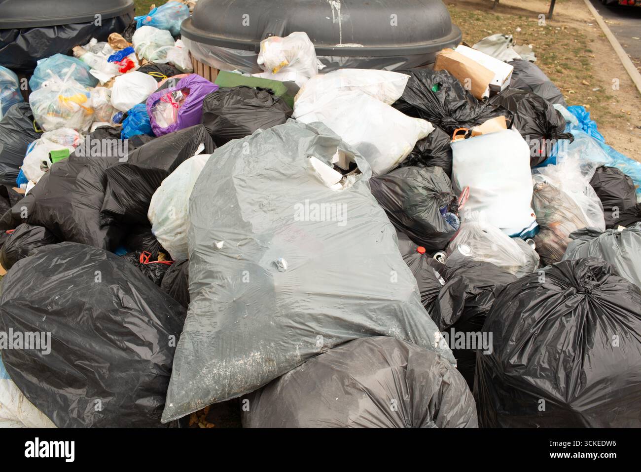 Heap of garbage bags piled around large bins at a highway rest area ...