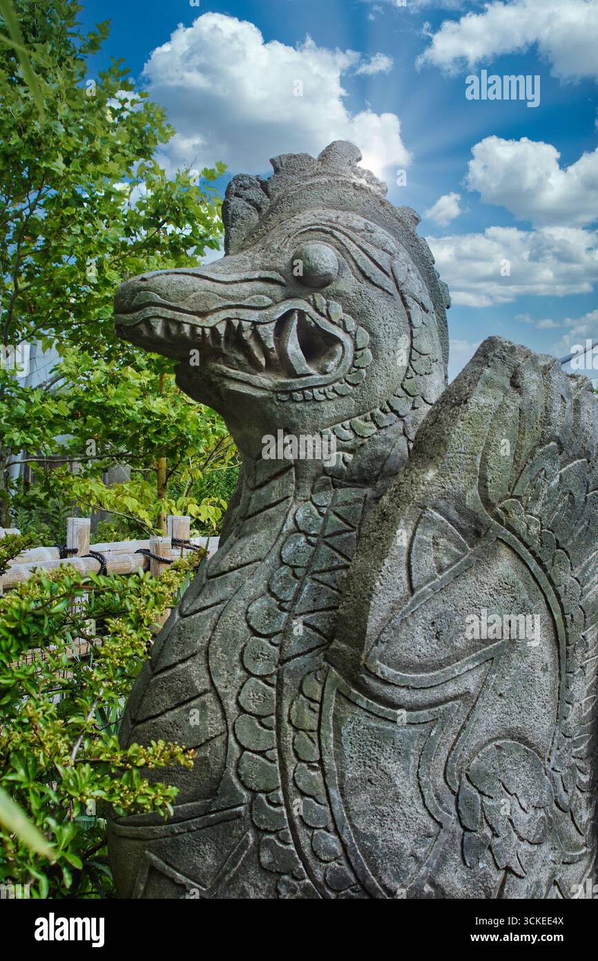 Tall stone sculpture of a mythical creature surrounded by greenery ...