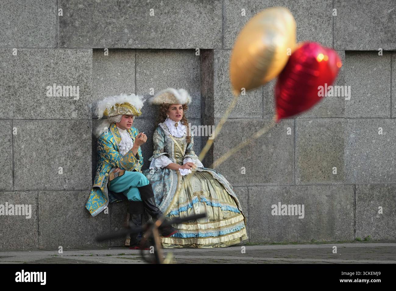 Street performers wearing 18th century costumes rest at the Palace ...