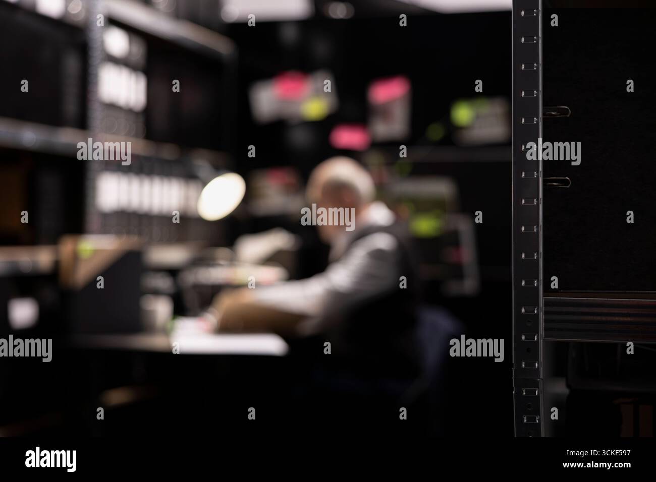 Out of focus older inspector reviewing photos and case files in ...